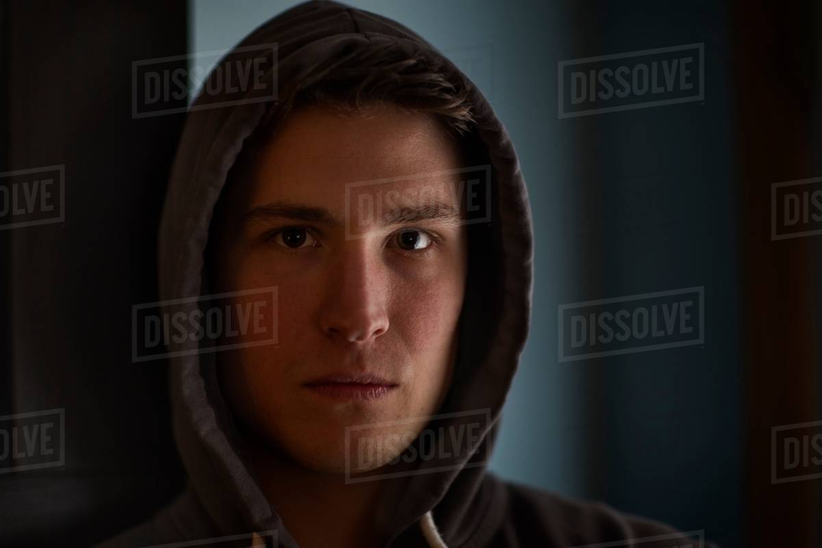 Portrait of intimidating young man wearing hood in shadows - Royalty ...