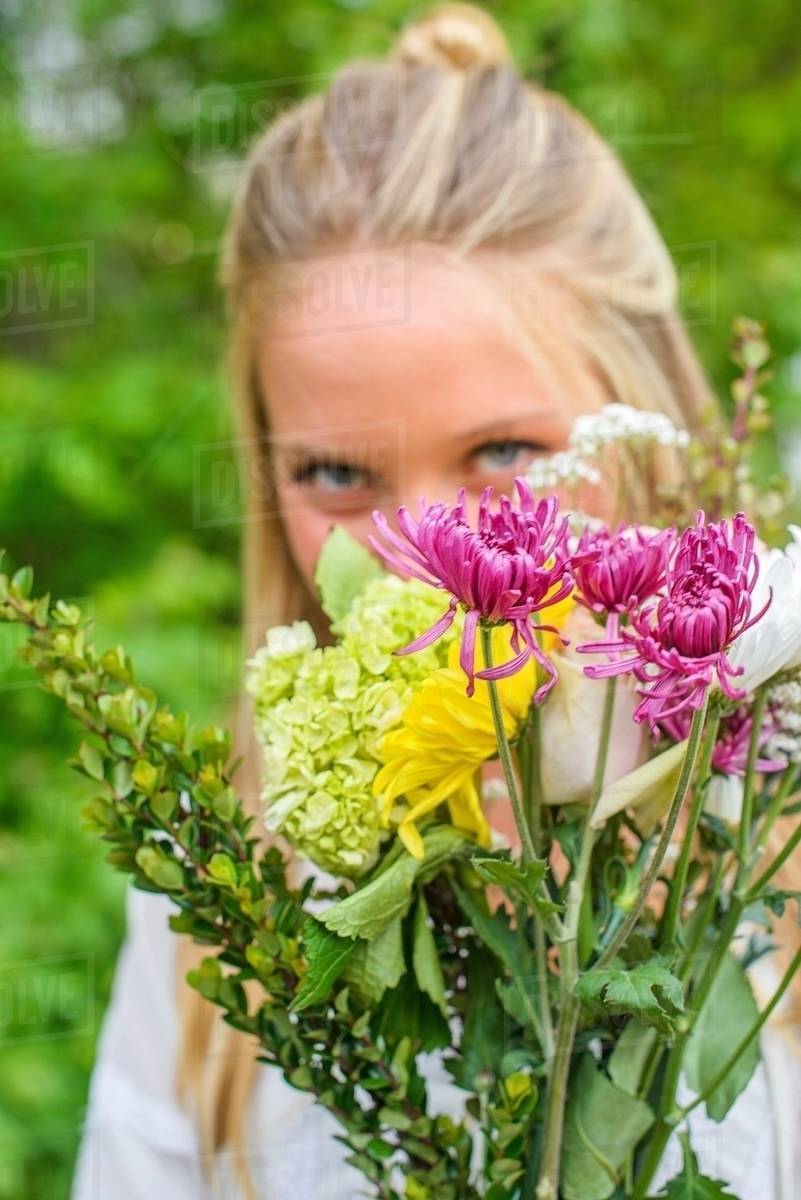 Portrait of young woman behind bunch of flowers - Stock Photo - Dissolve
