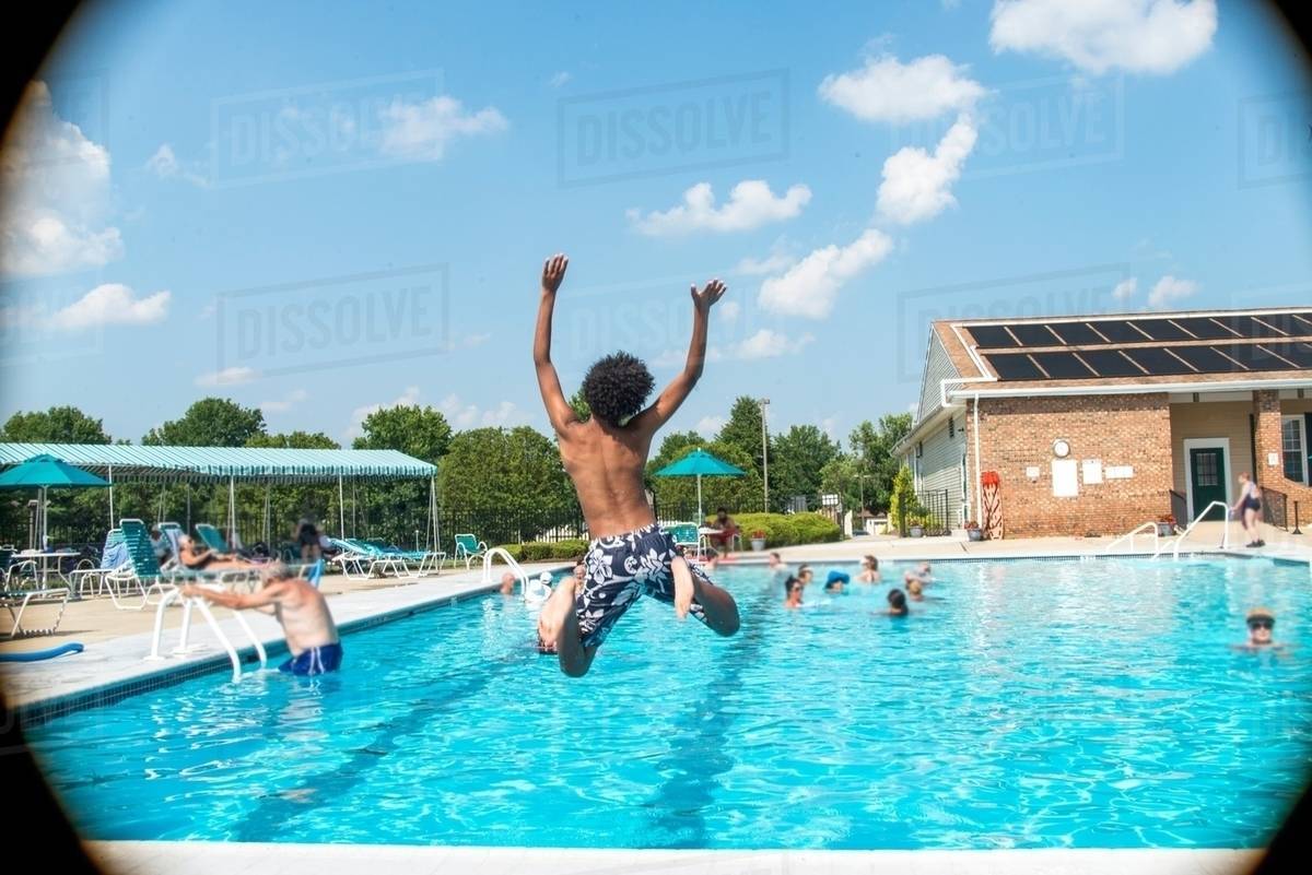 Rear view of boy jumping into outdoor swimming pool - Royalty-free ...