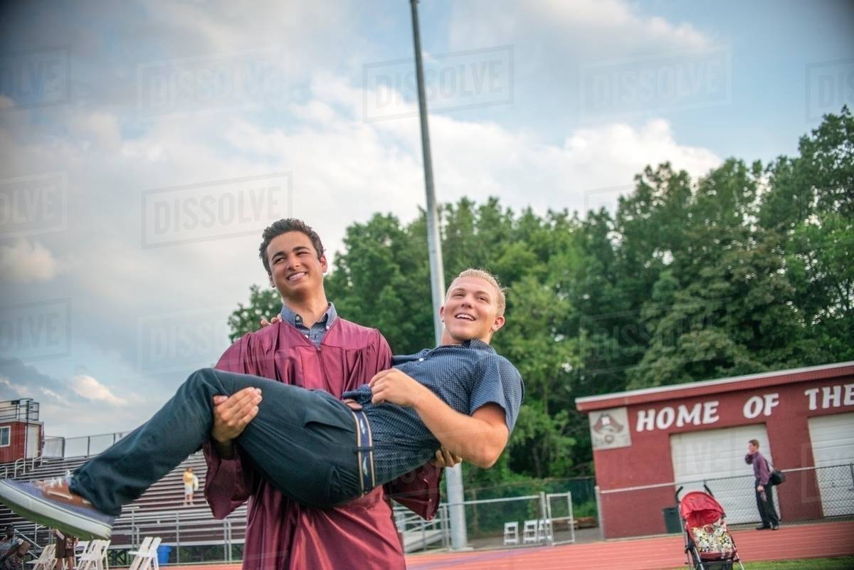 Young man lifting male friend at graduation ceremony - Royalty-free ...