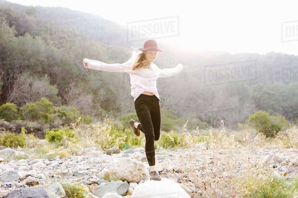 Young woman jumping on rock, smiling, outdoors - Royalty-free Stock ...