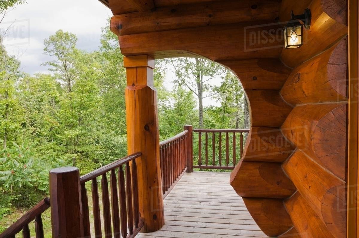 Exterior of cottage style log home with arch and wooden plank veranda ...