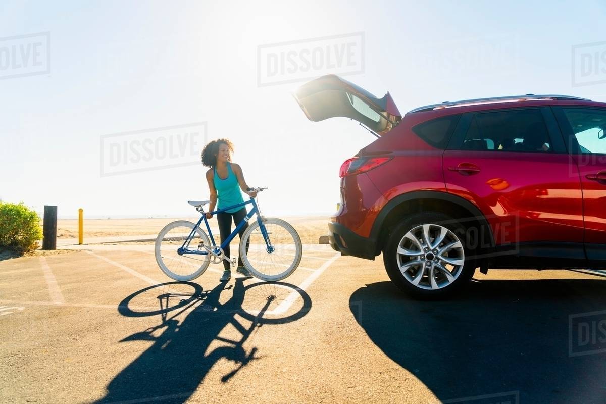 Mid adult woman putting bicycle into car boot - Stock Photo - Dissolve