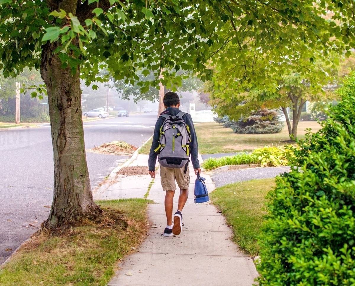 Boy with backpack walking on sidewalk - Royalty-free Stock Photo | Dissolve