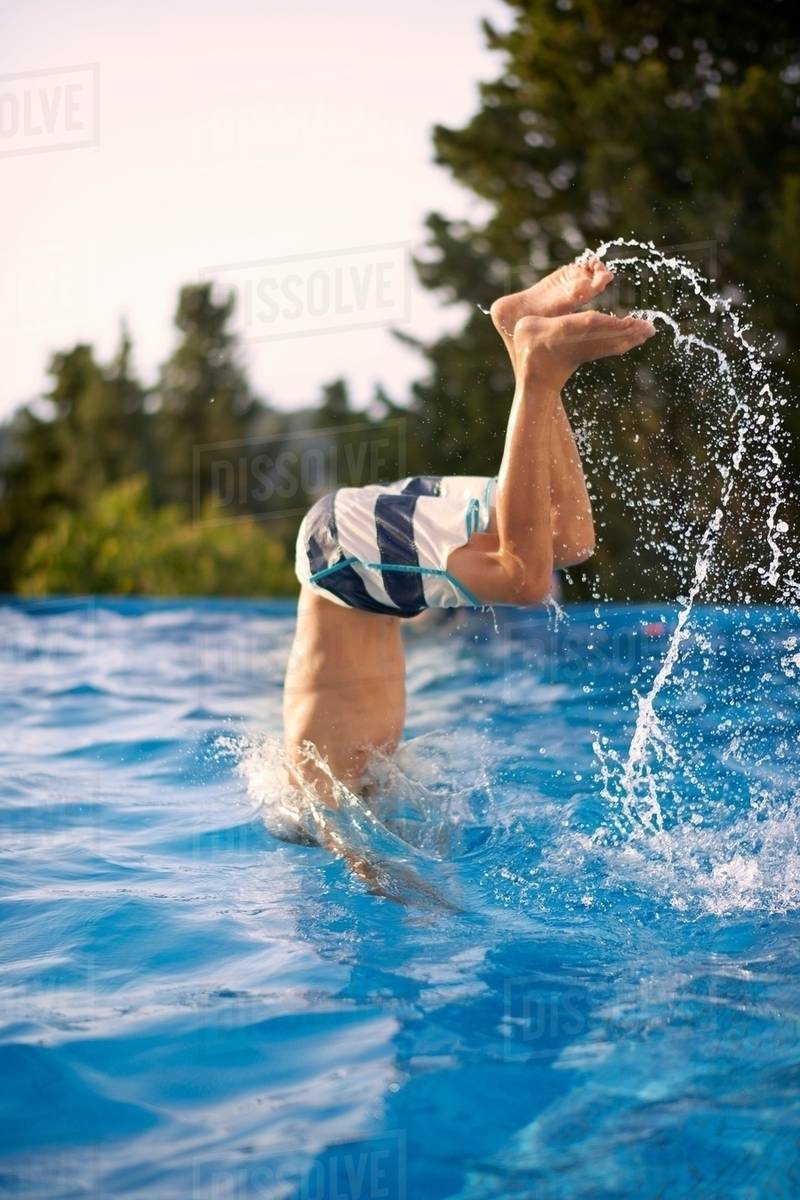 Upside down teenage boy diving into outdoor swimming pool - Royalty ...
