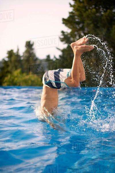 Upside down teenage boy diving into outdoor swimming pool - Royalty ...