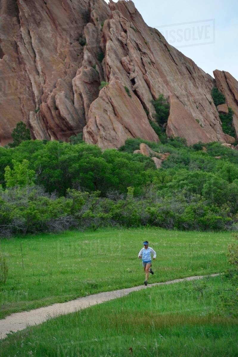 Female trail runner running along dirt track, Colorado Front Range ...