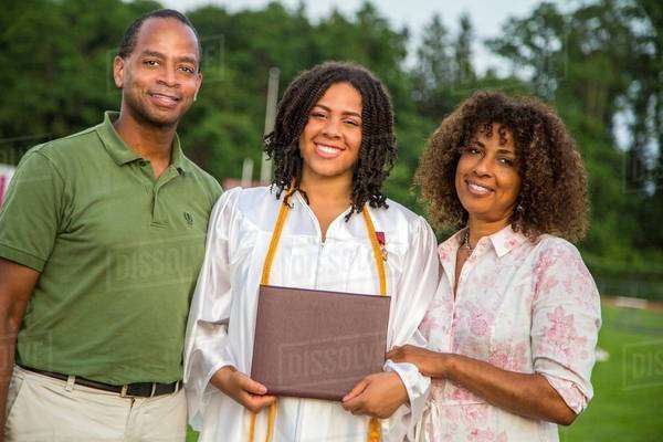 Portrait of teenage girl with parents at graduation ceremony - Royalty ...