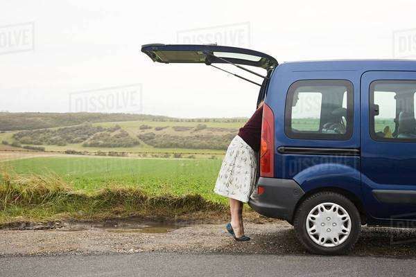 Woman looking in car boot - Royalty-free Stock Photo | Dissolve