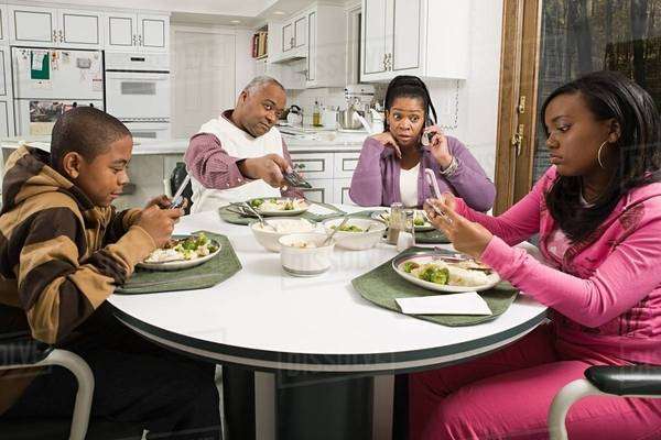Distracted family at the dinner table - Royalty-free Stock Photo | Dissolve