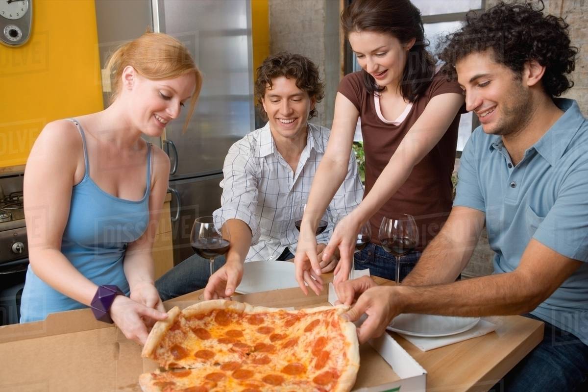 Friends sharing a pizza - Royalty-free Stock Photo | Dissolve