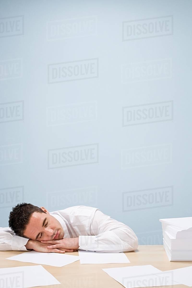 Office worker sleeping on desk - Stock Photo - Dissolve