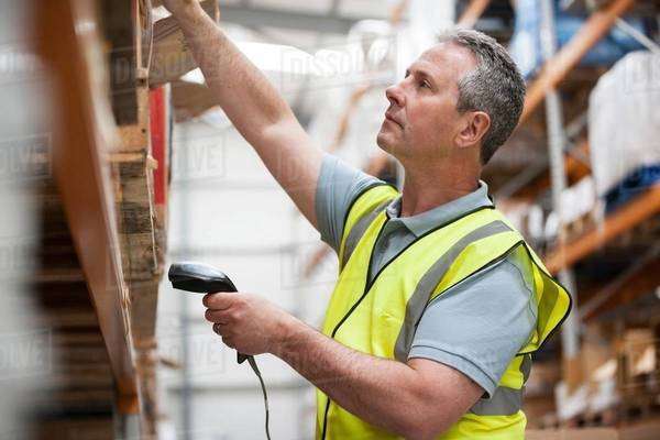 Man using barcode reader in warehouse - Royalty-free Stock Photo | Dissolve