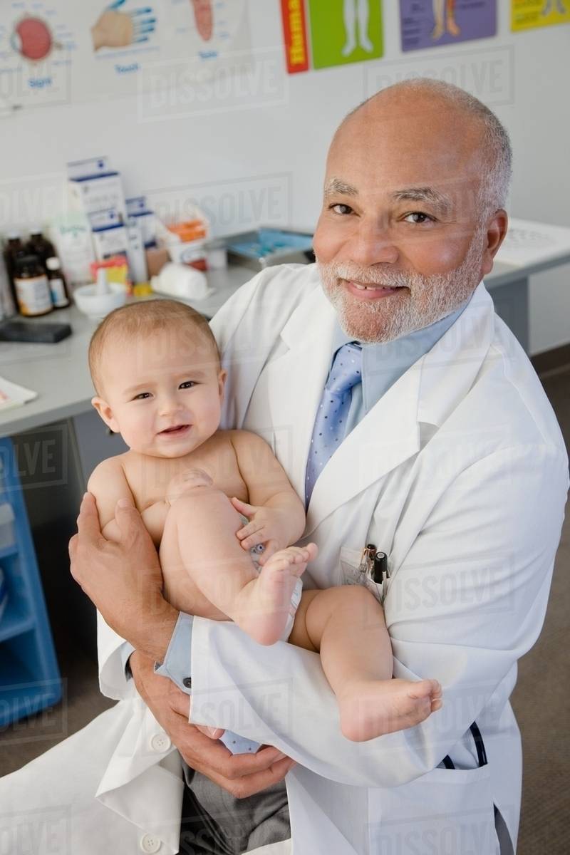 Portrait of a doctor holding a baby - Stock Photo - Dissolve