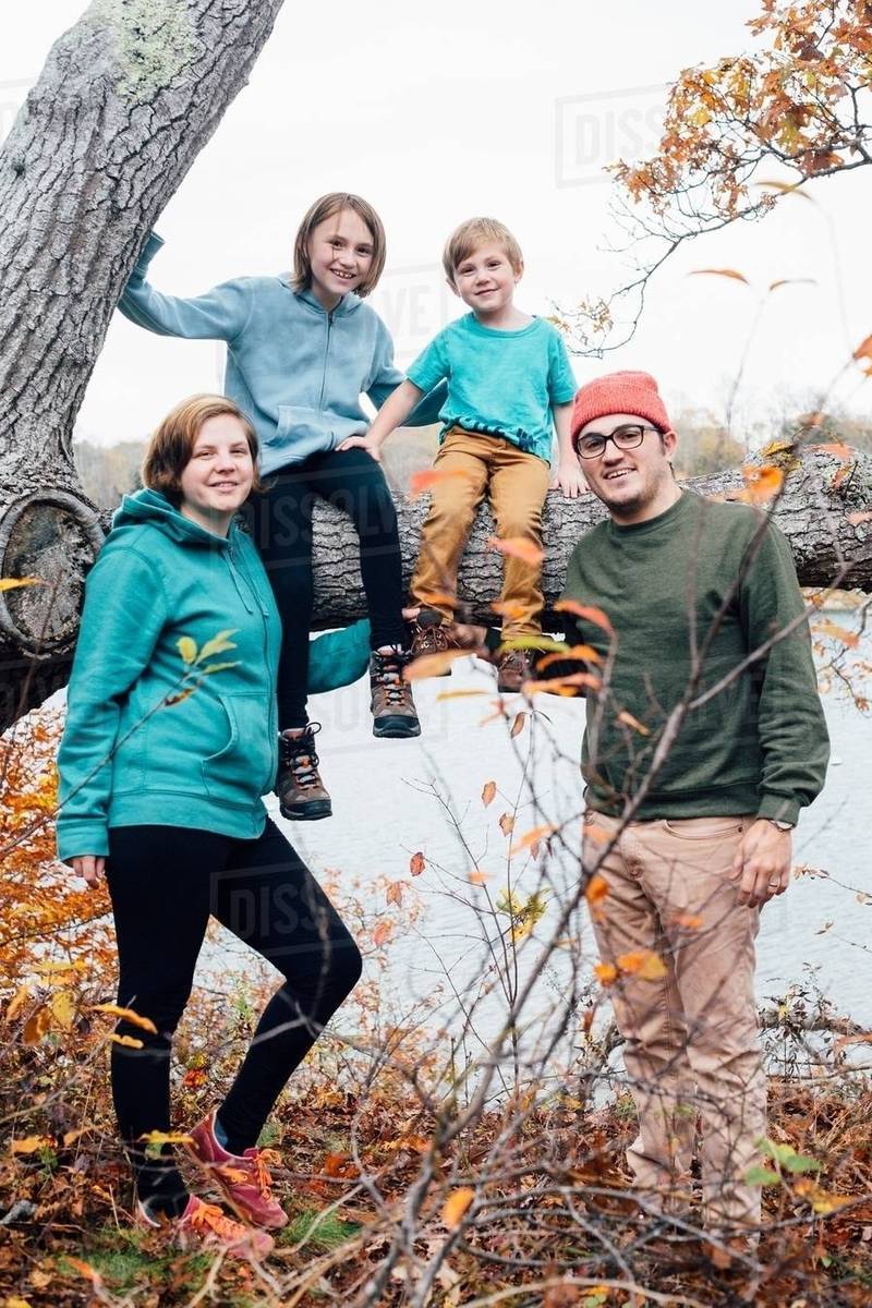 Portrait of family, children sitting on tree - Stock Photo - Dissolve