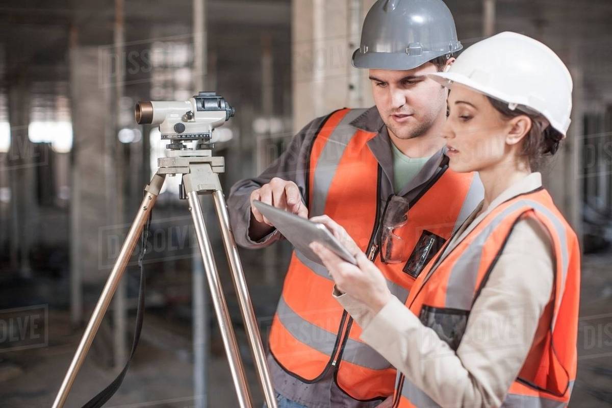 Female and male surveyor using digital tablet on construction site ...