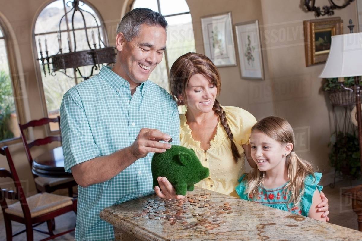 Family saving money in green piggy bank - Stock Photo - Dissolve