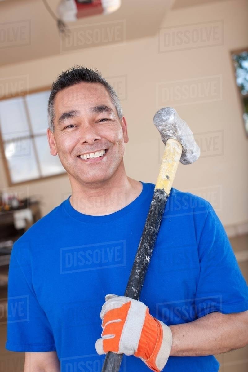 Man holding sledge hammer in garage - Royalty-free Stock Photo | Dissolve