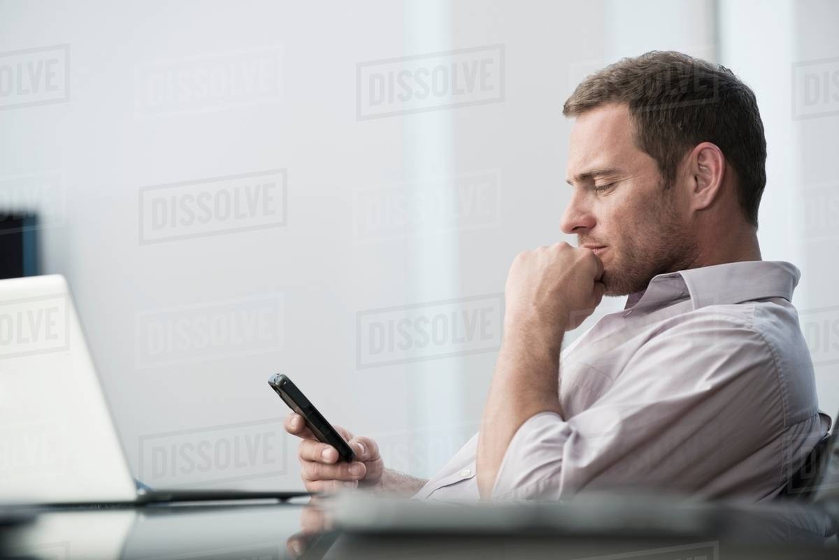 Businessman using cell phone at desk - Royalty-free Stock Photo | Dissolve