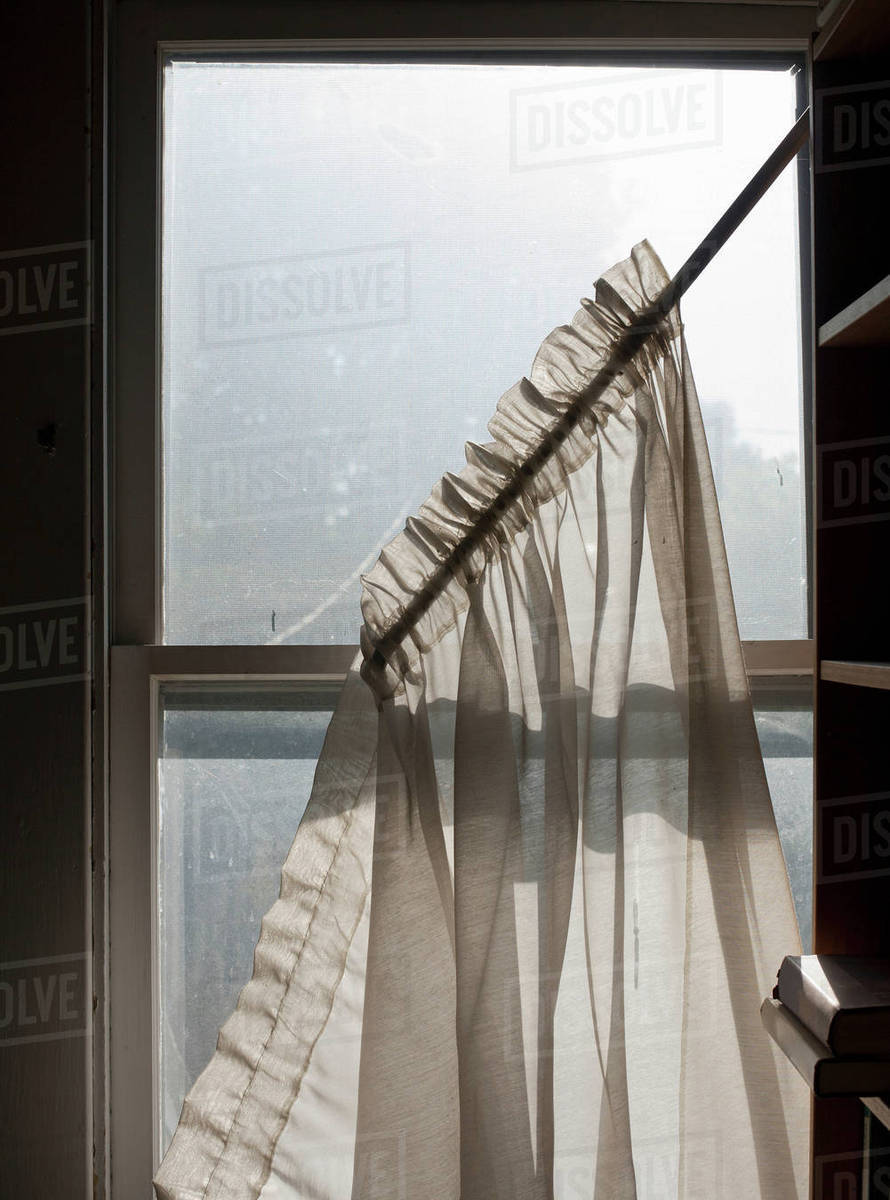 Net curtains falling from dirty sash window - Stock Photo - Dissolve