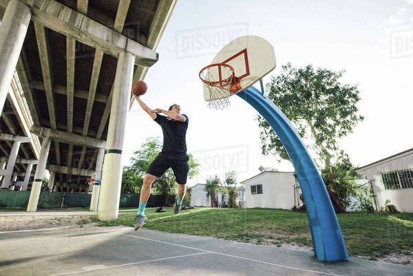 Low angle view of man on basketball court in mid air jumping for ...
