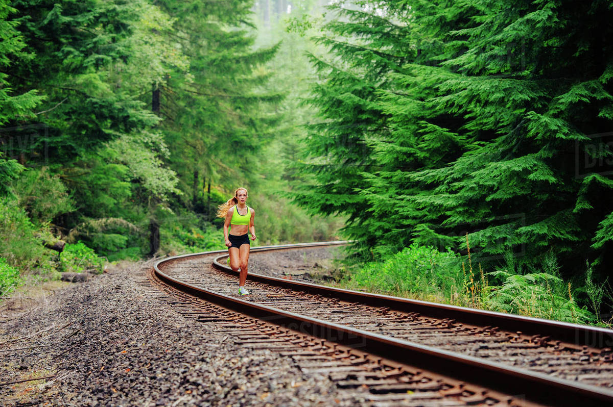 Teenage girl running along rural train track - Royalty-free Stock Photo ...