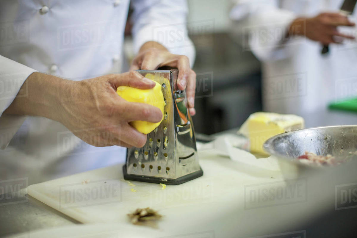 Chef grating cheese in kitchen - Royalty-free Stock Photo | Dissolve