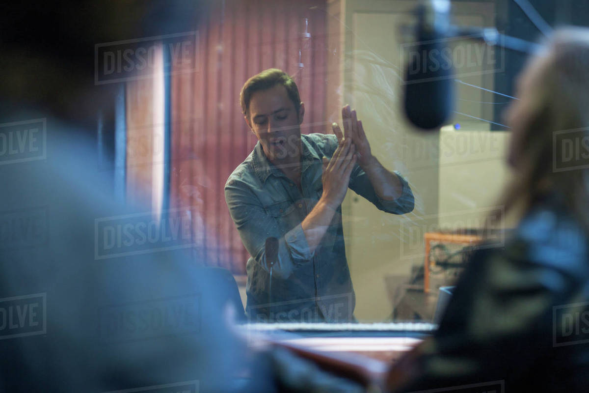 Musicians in recording studio, music producer communicating to them ...