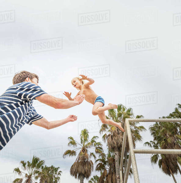 Boy jumping into young man's arms on Venice Beach, California, USA ...