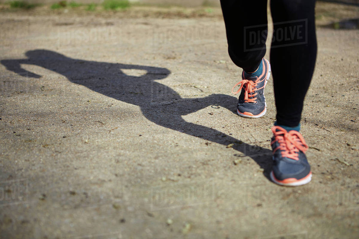 Shadow and legs of woman wearing running shoes - Royalty-free Stock ...
