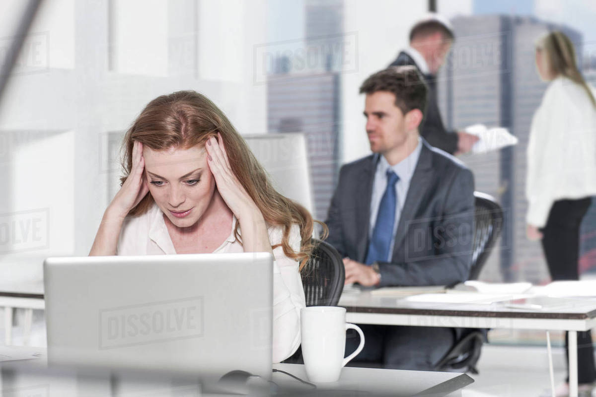 Businesswoman having headache in office, colleague working in ...