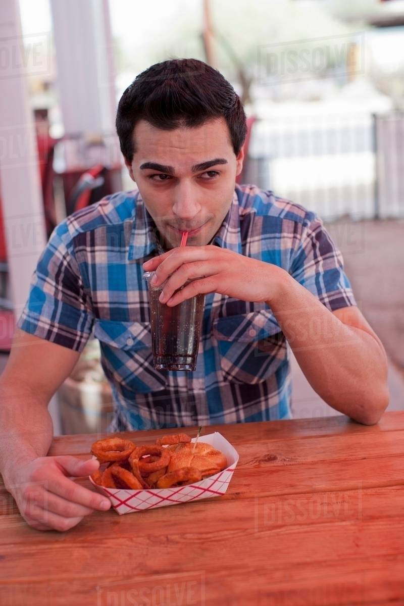 Young man drinking cola in diner, looking away - Royalty-free Stock ...