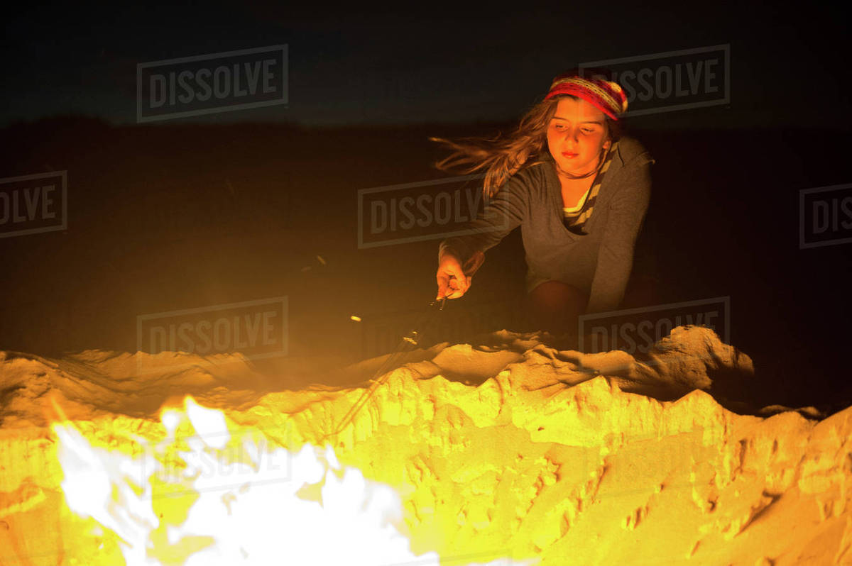 Young girl cooking food over campfire - Stock Photo - Dissolve