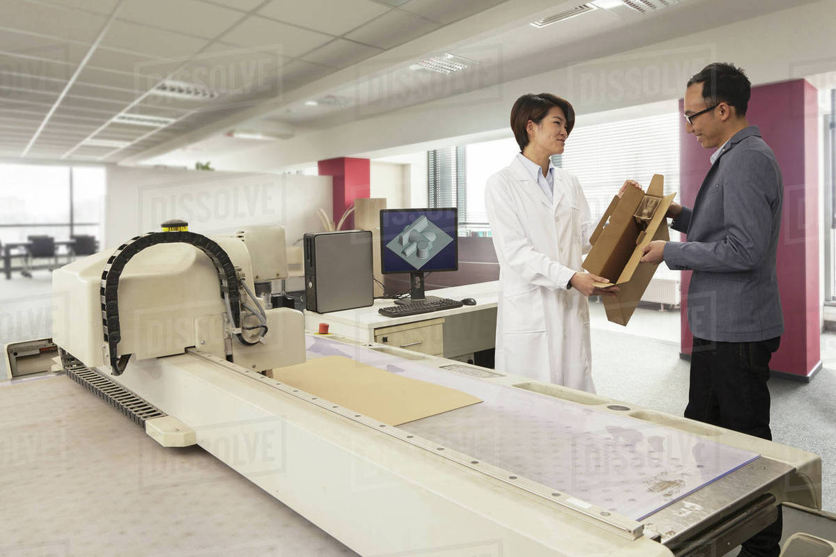 Technician showing cardboard box to manager by packaging machine in ...