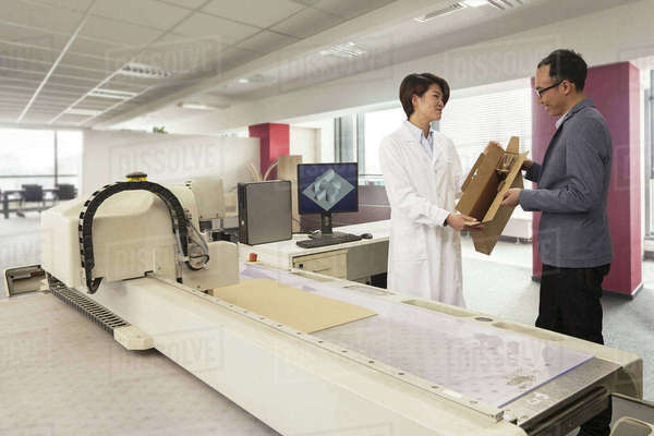 Technician showing cardboard box to manager by packaging machine in ...