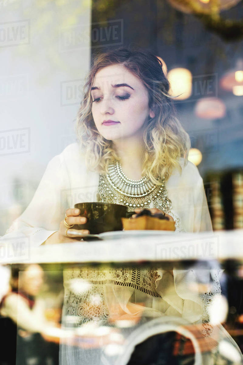 View through coffee shop window of woman with coffee - Stock Photo ...