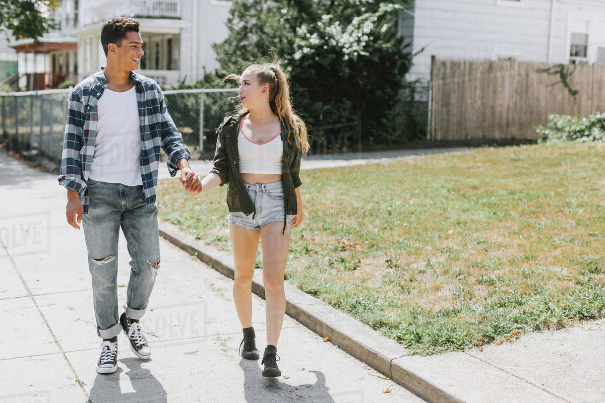 Couple walking in street holding hands - Stock Photo - Dissolve