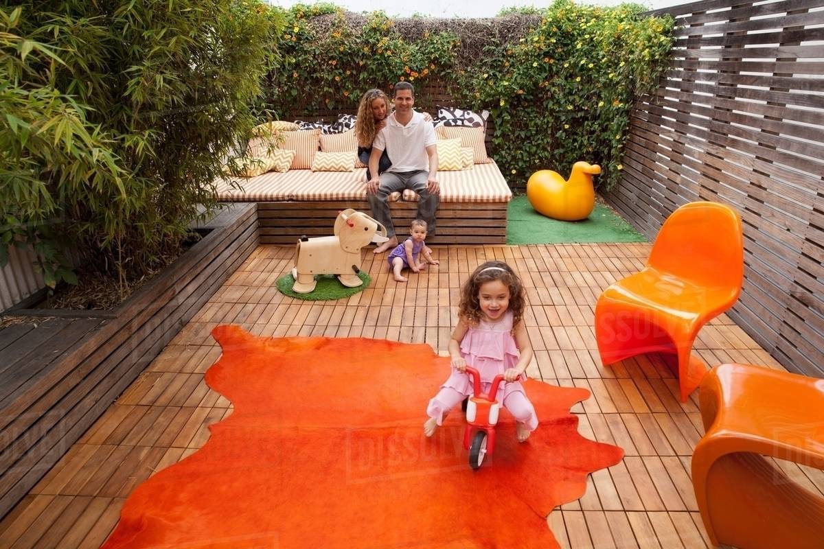 Parents Relaxing Outdoor With Children Playing On Patio Stock Photo parents-relaxing-outdoor-with-children-playing-on-patio-stock-photo