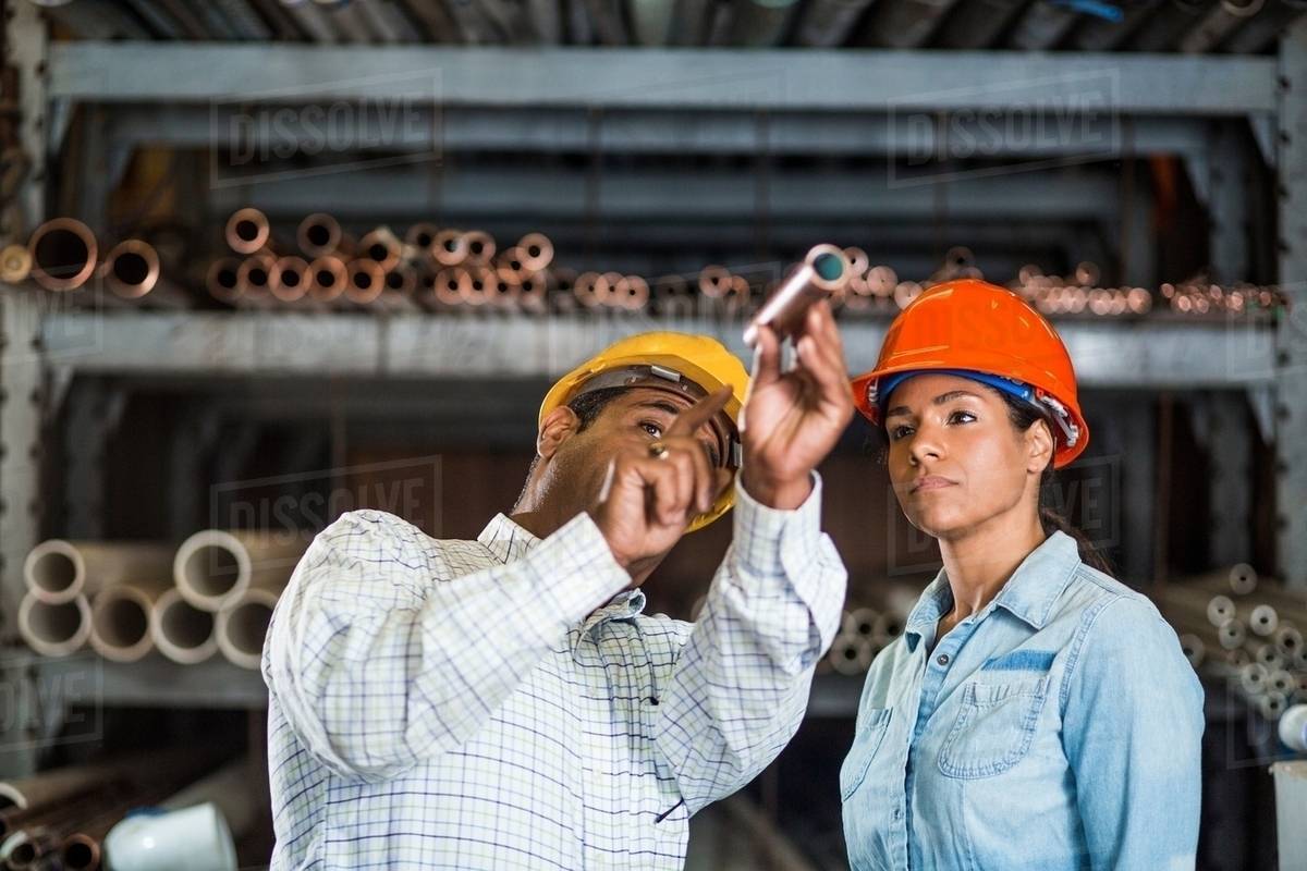 Two warehouse workers looking at copper pipe - Stock Photo - Dissolve