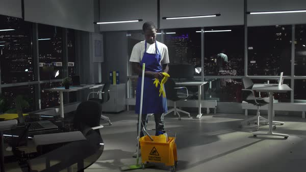African-American janitor in uniform look at camera and smile in dark ...