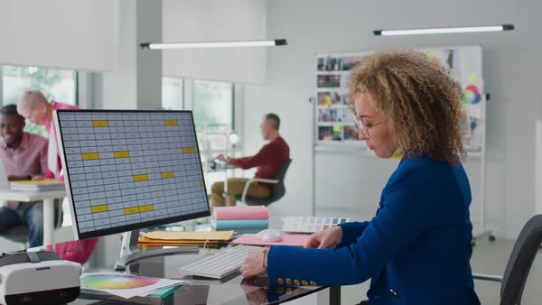 Female chief editor doing paperwork and checking table on computer ...