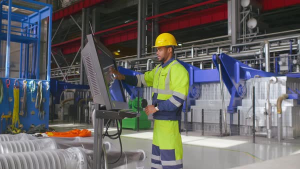 Black male engineer in uniform uses computer LCD touch screen for ...