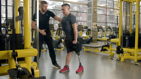 Disabled young man with instructor working out in gym - 4K Royalty-free ...