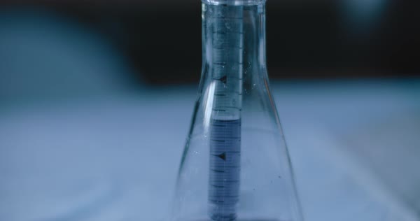 Scientist put a purple liquid into a conical flask to test chemicals ...