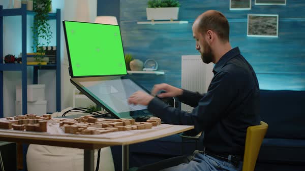 Man architect looking at horizontal green screen and using touch screen ...