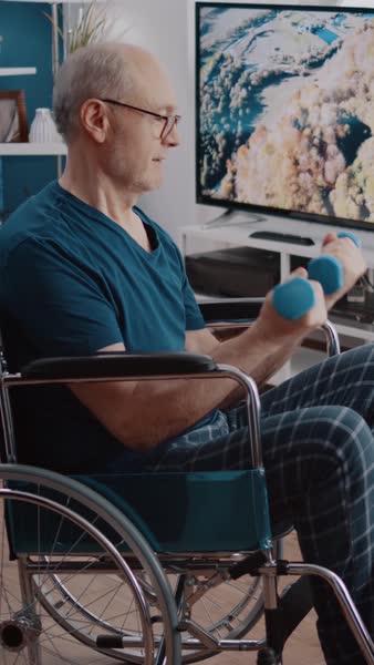 Vertical video: Man with disability using dumbbells to stretch arms ...