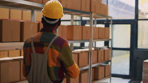 African american man checking goods on laptop, reviewing stock ...