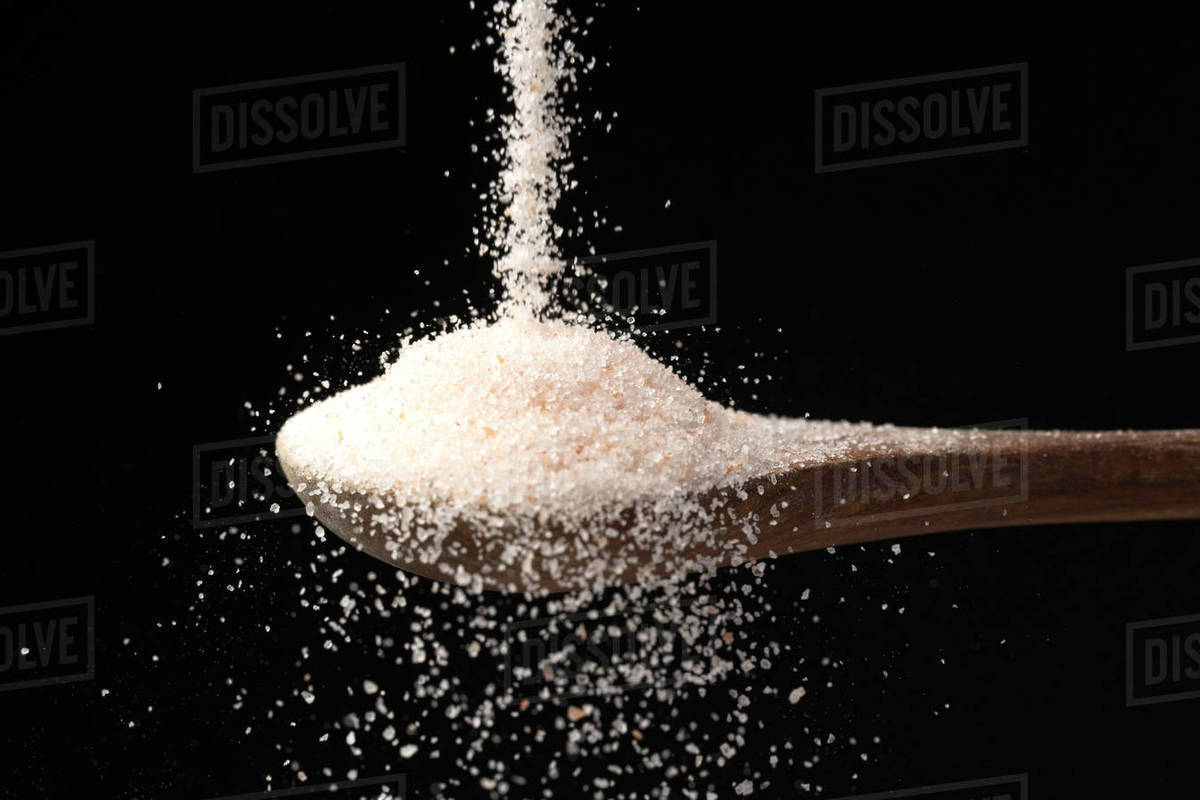 A studio photo of fine himalayan sea salt pouring down on a wooden ...
