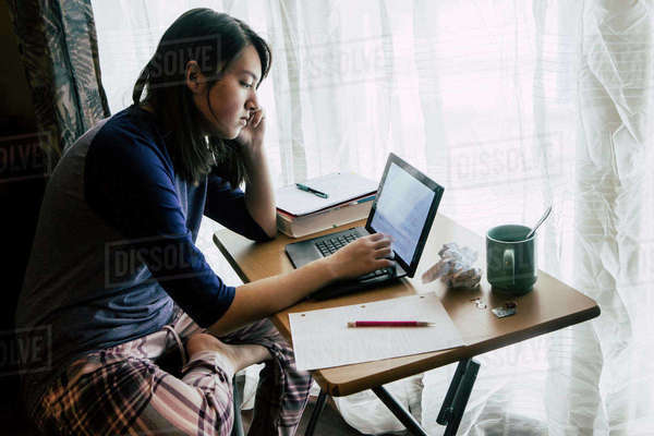 A lifestyle photo of a girl using the notebook computer at home to do ...