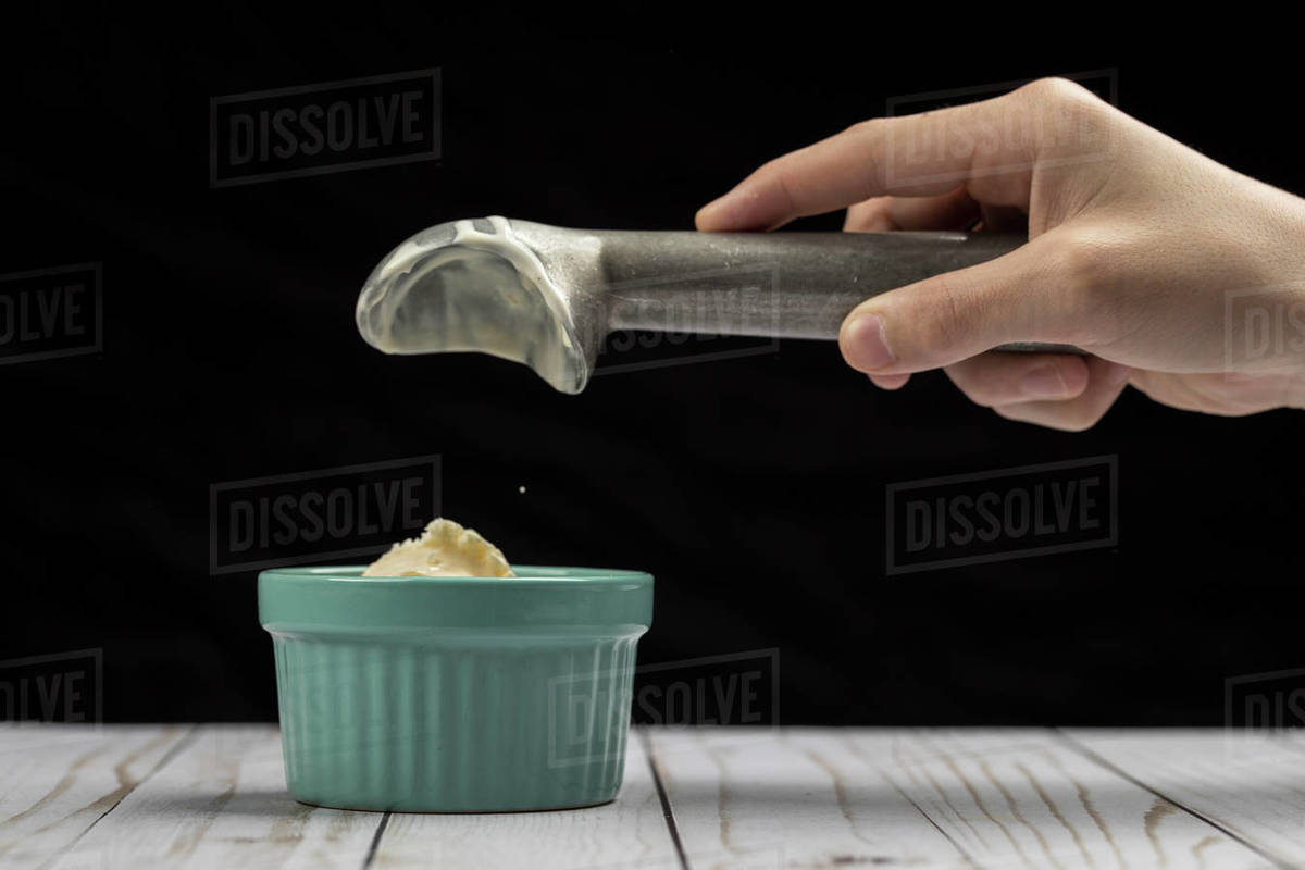 A scoop of vanilla ice cream drops down into a bowl. - Royalty-free ...